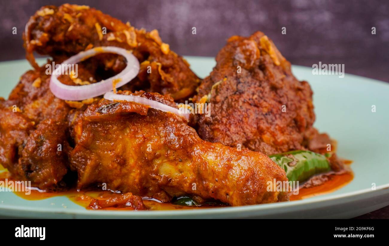 Chicken cooked in dry spicy red curry garnished with onion ring and ...