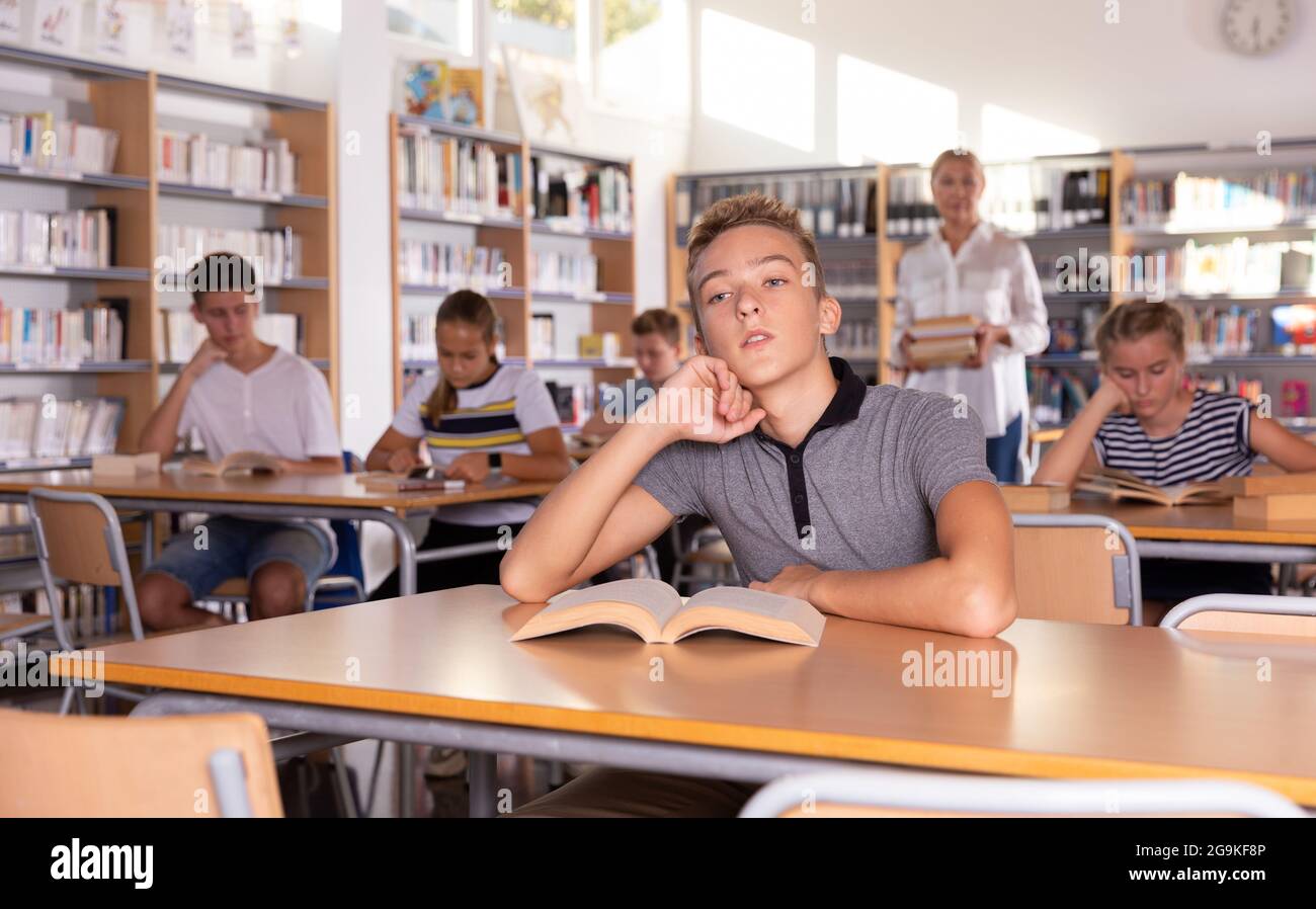 Boy preparing for lesson in school library, reading textbooks Stock ...