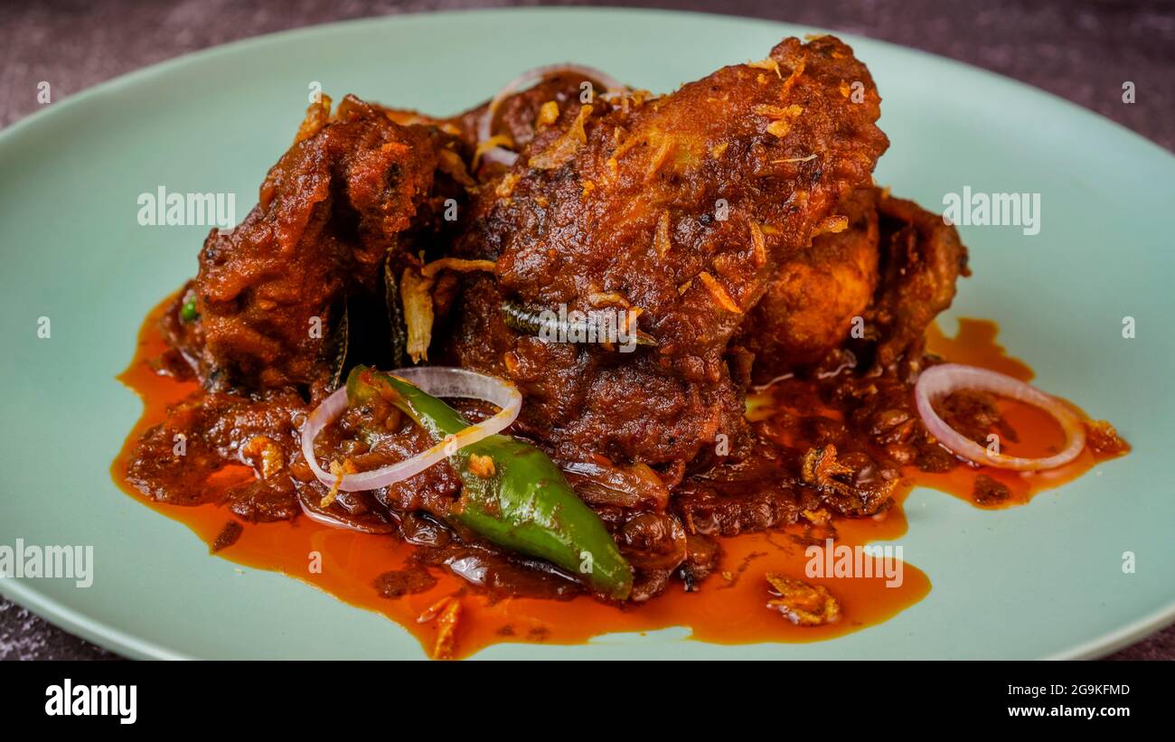 Chicken cooked in dry spicy red curry garnished with onion ring and ...