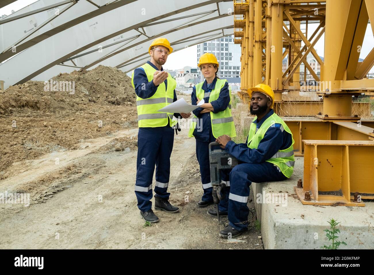Group of construction workers looking at building and discussing ...