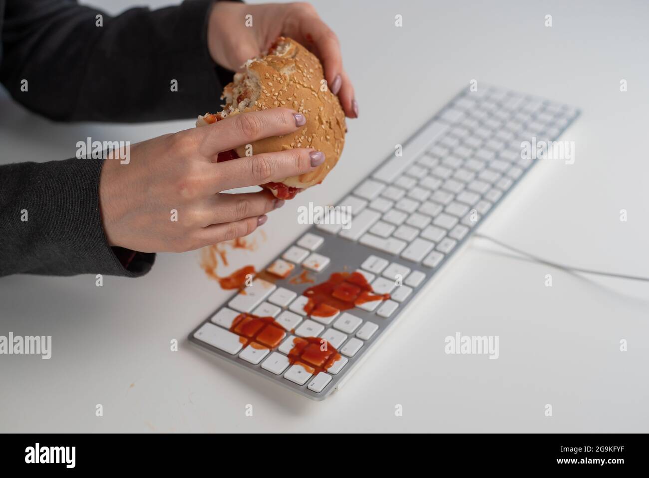 A faceless woman is eating a burger and dripping ketchup on the ...