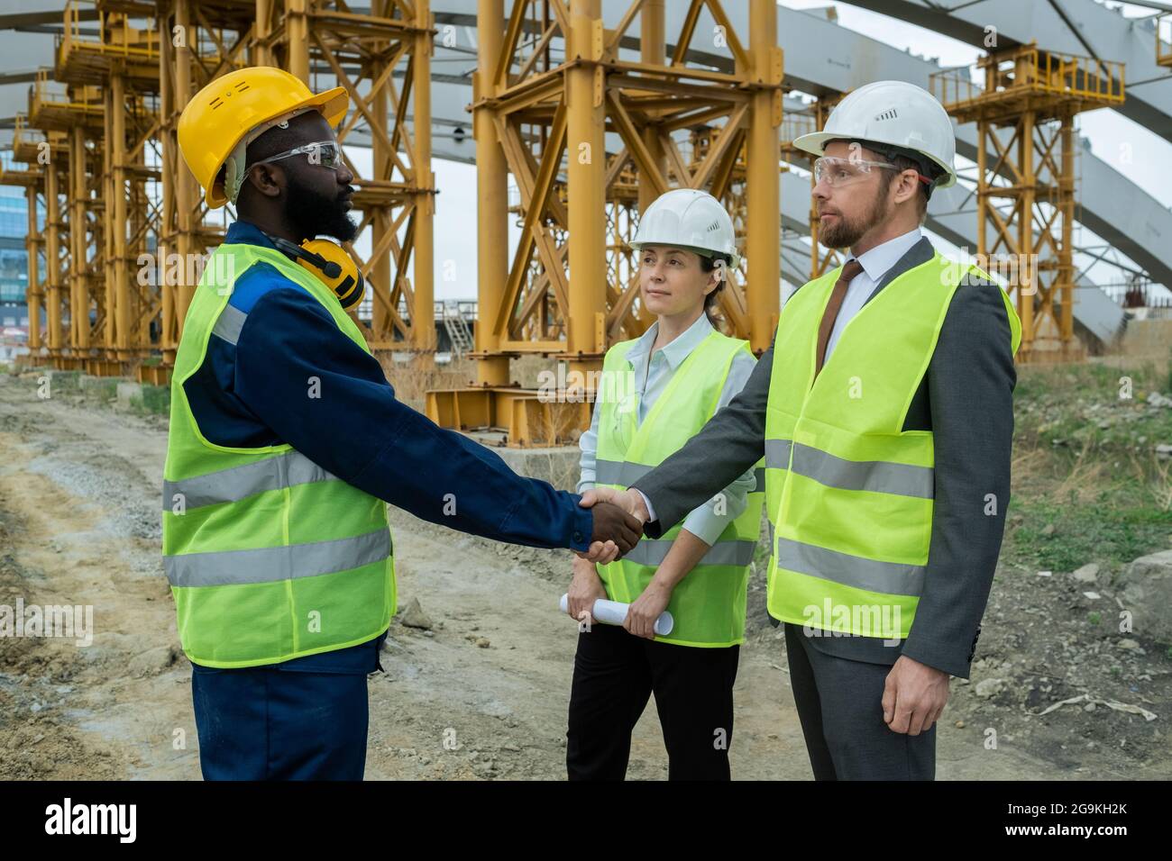 Construction workers shaking hands during meeting with colleague on ...