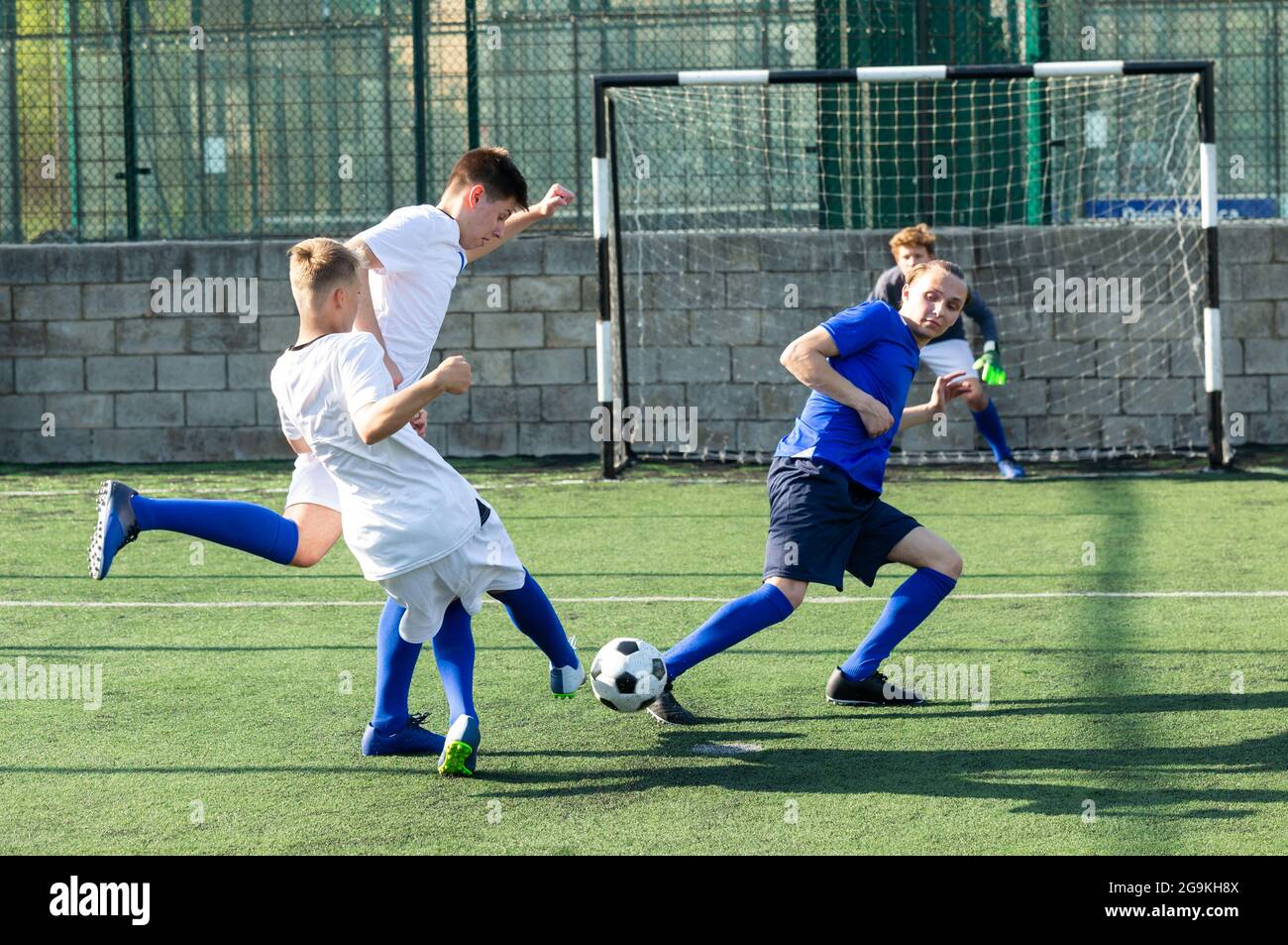 Game of football match between two teams of teenagers in white and blue ...