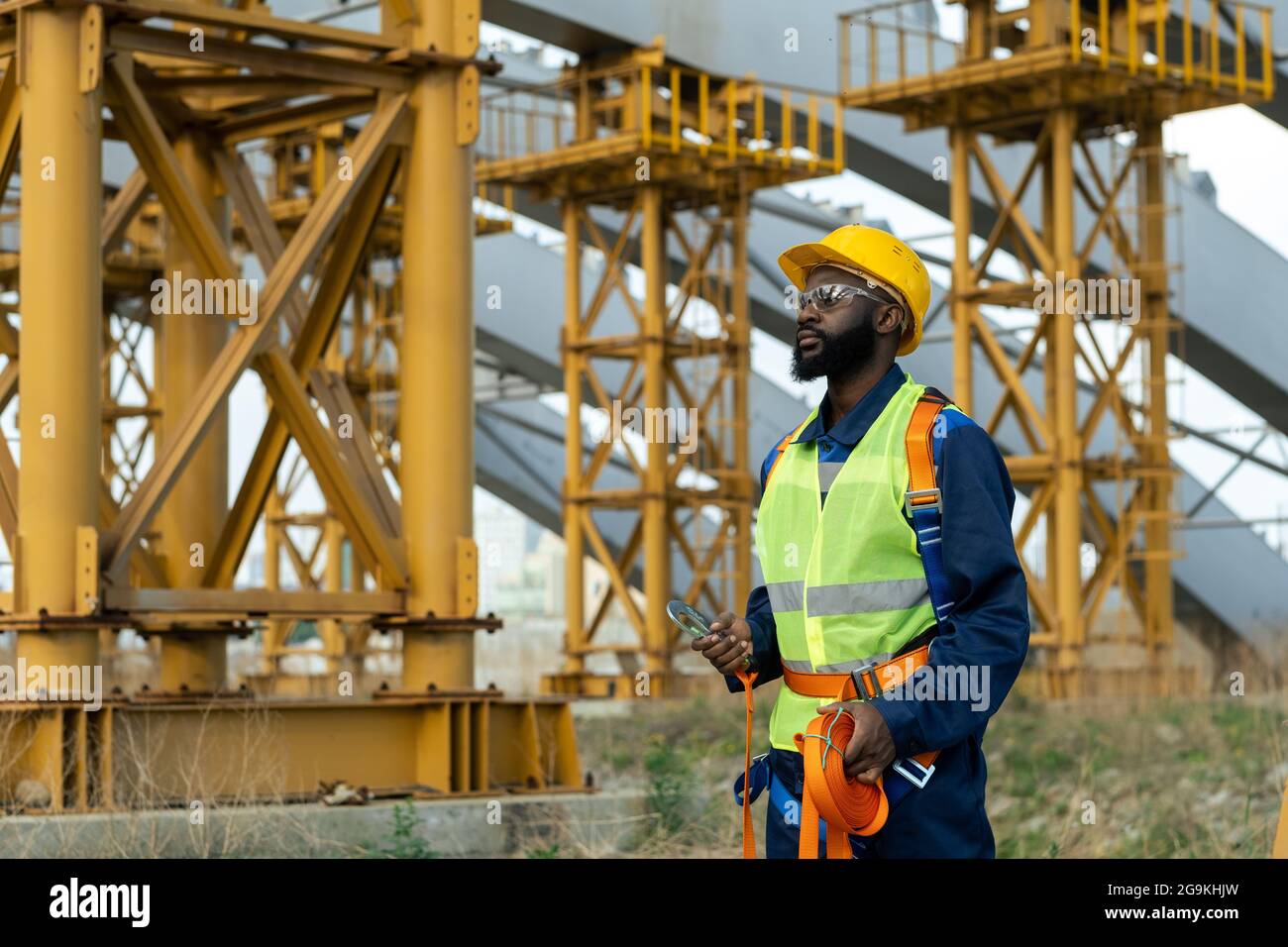 African young construction worker in equipment walking through the ...