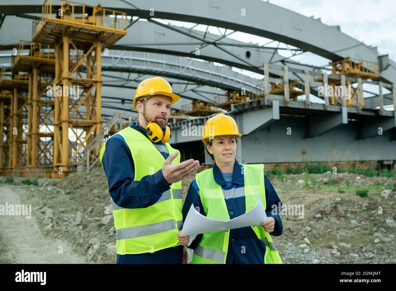 Construction workers in reflective clothing and work helmets looking at ...