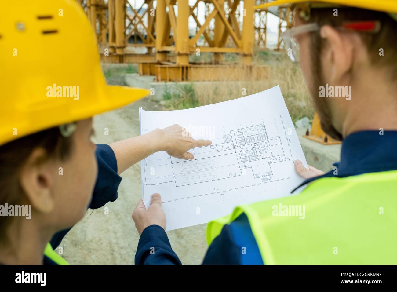Close-up of two engineers pointing at blueprint and controlling the ...