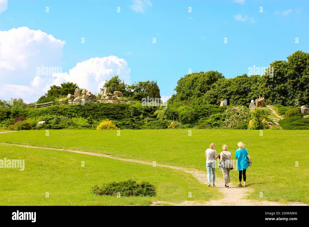 Three blonde middle-aged women walk along a winding hiking trail on a ...