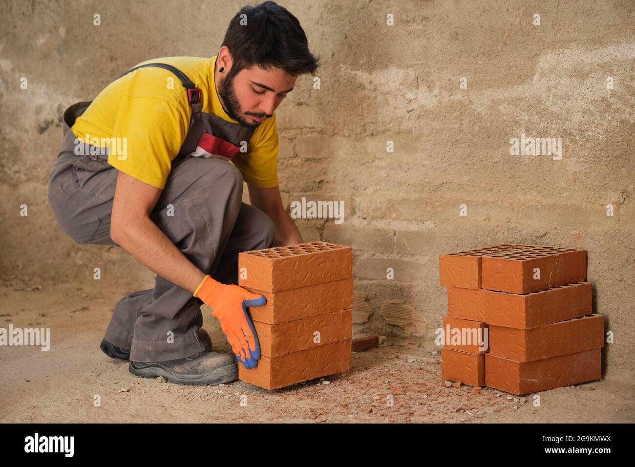 Young caucasian construction worker moving bricks at the construction ...