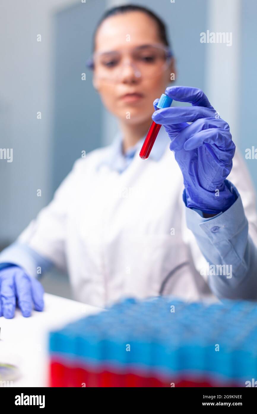 Specialist woman doctor holding blood medical vacutainer analyzing dna ...