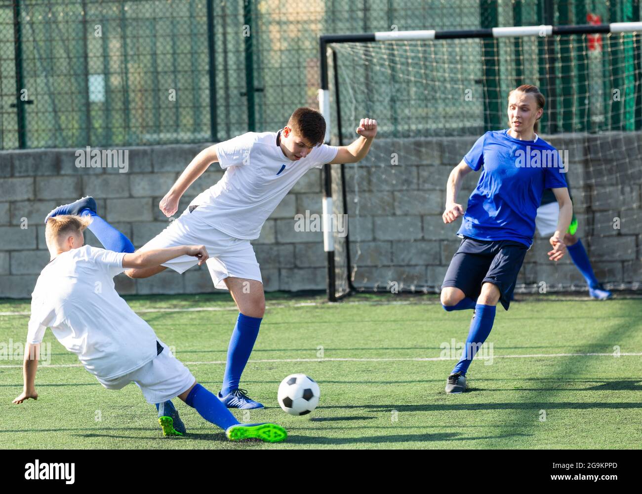 Game of football match between two teams of teenagers in white and blue ...