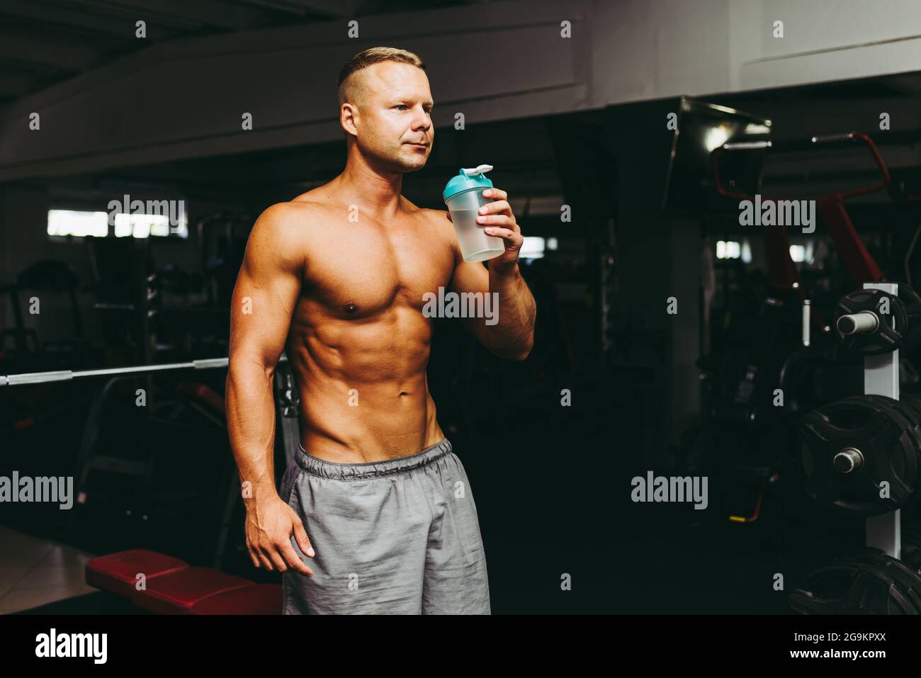 Young caucasian man drinking water after exercise.man in the gym ...