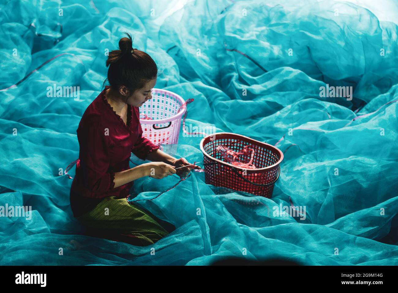 Southeast Asian women is sewing the fishnet at the Fishing village ...