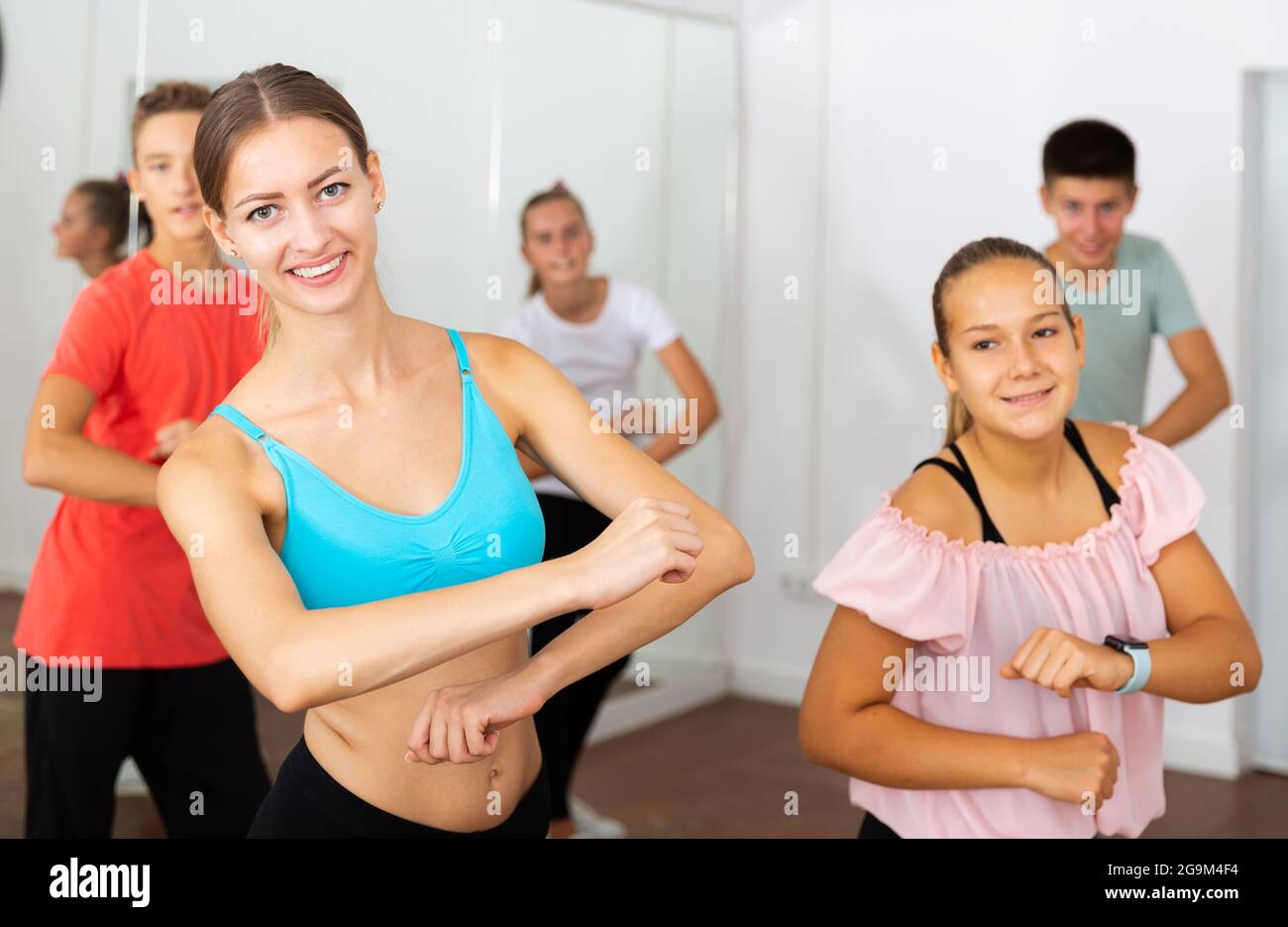 Portrait of young female instructor fulfilling dance movements with ...