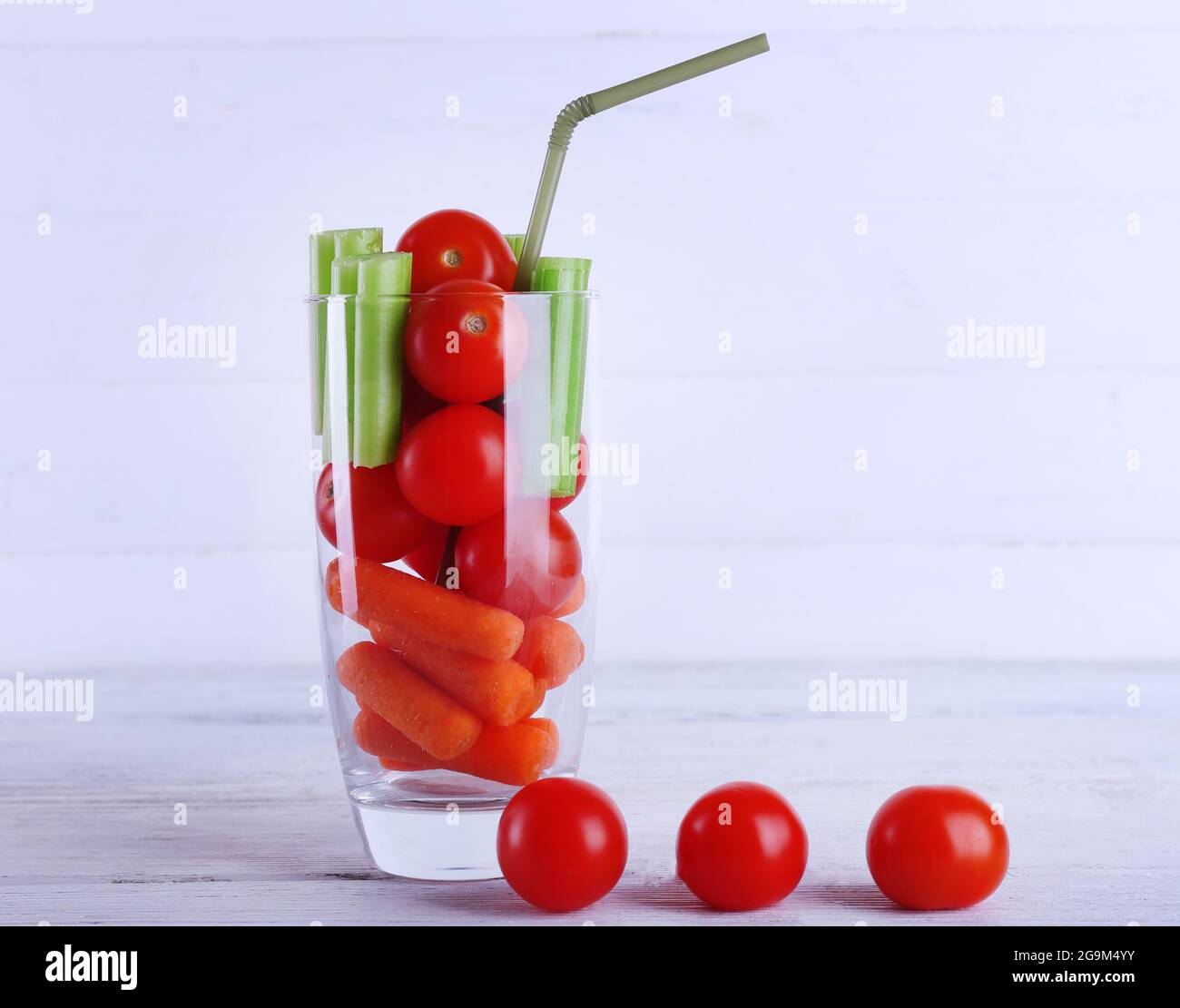 Vegetables in glass with tube on color wooden planks background Stock ...