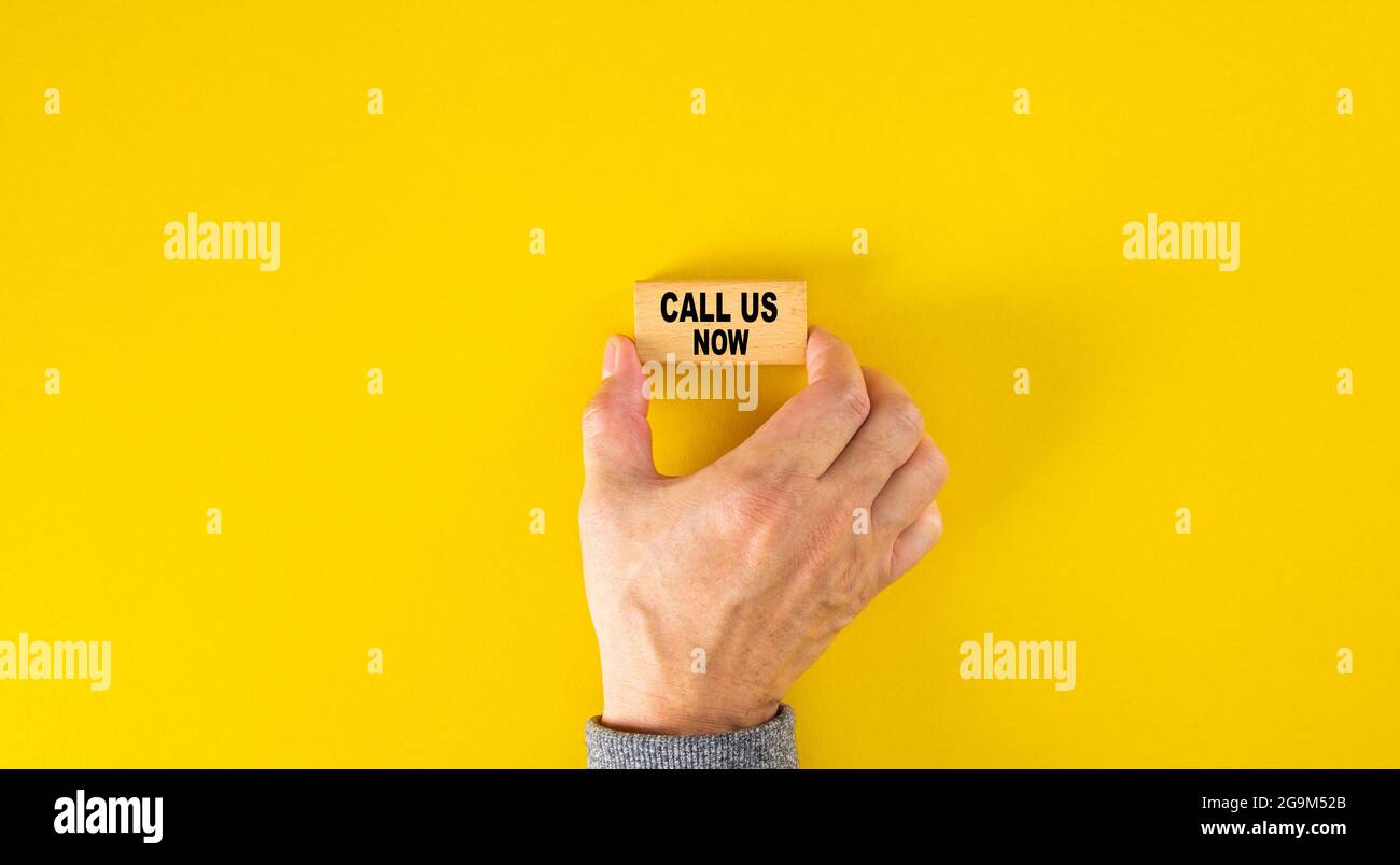 Hand holding a wooden block with text CALL US NOW. Service Support ...