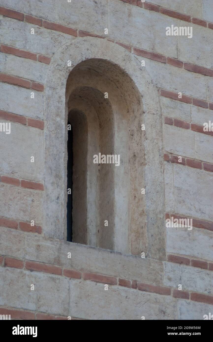 A close-up of a simple but stylish stone arched window set in the side ...