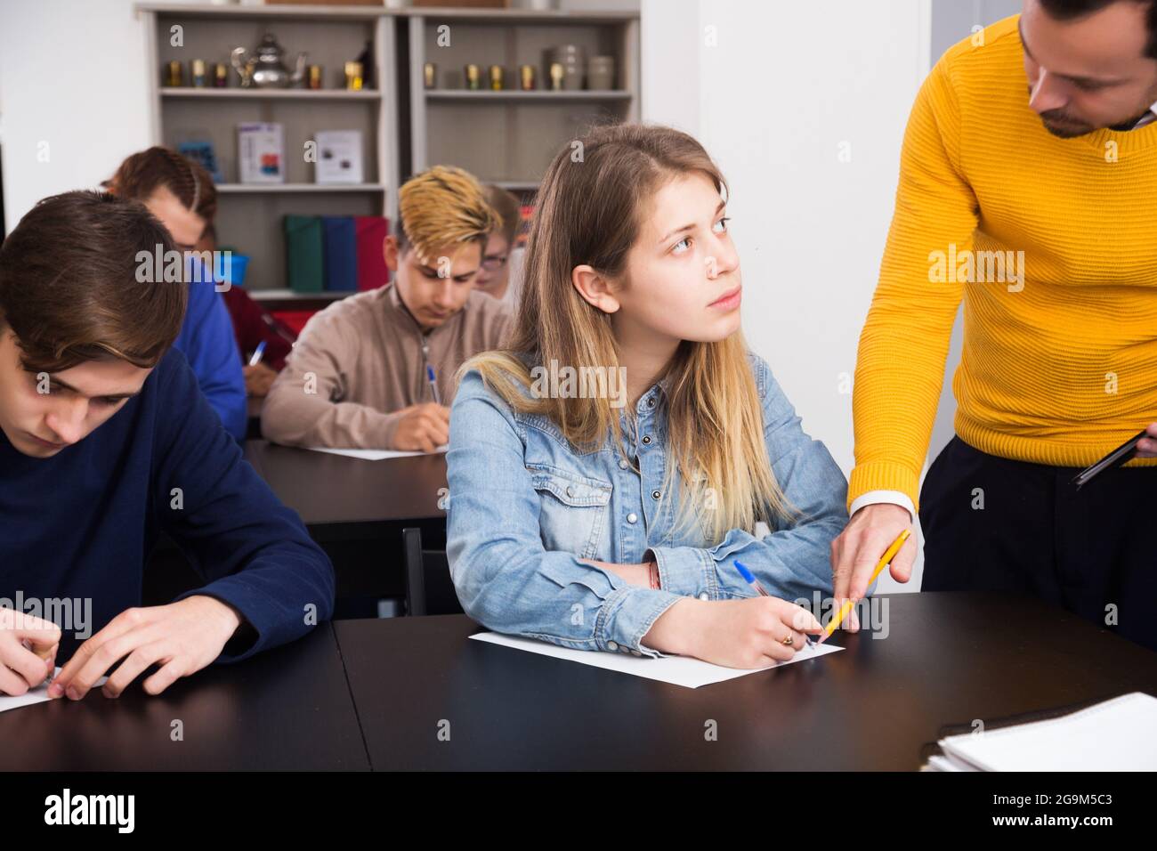 Serious young teacher giving explanation to student during revision ...