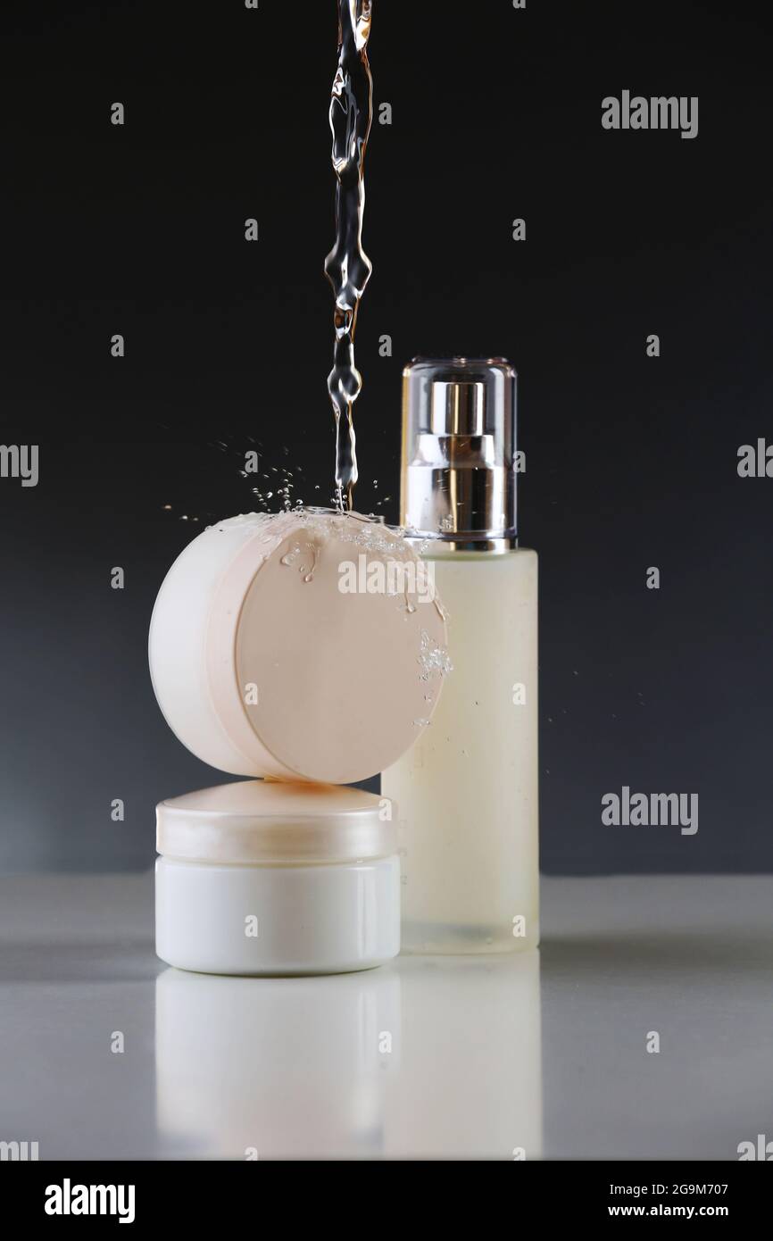 Cosmetic products in water splashes on gray background Stock Photo - Alamy