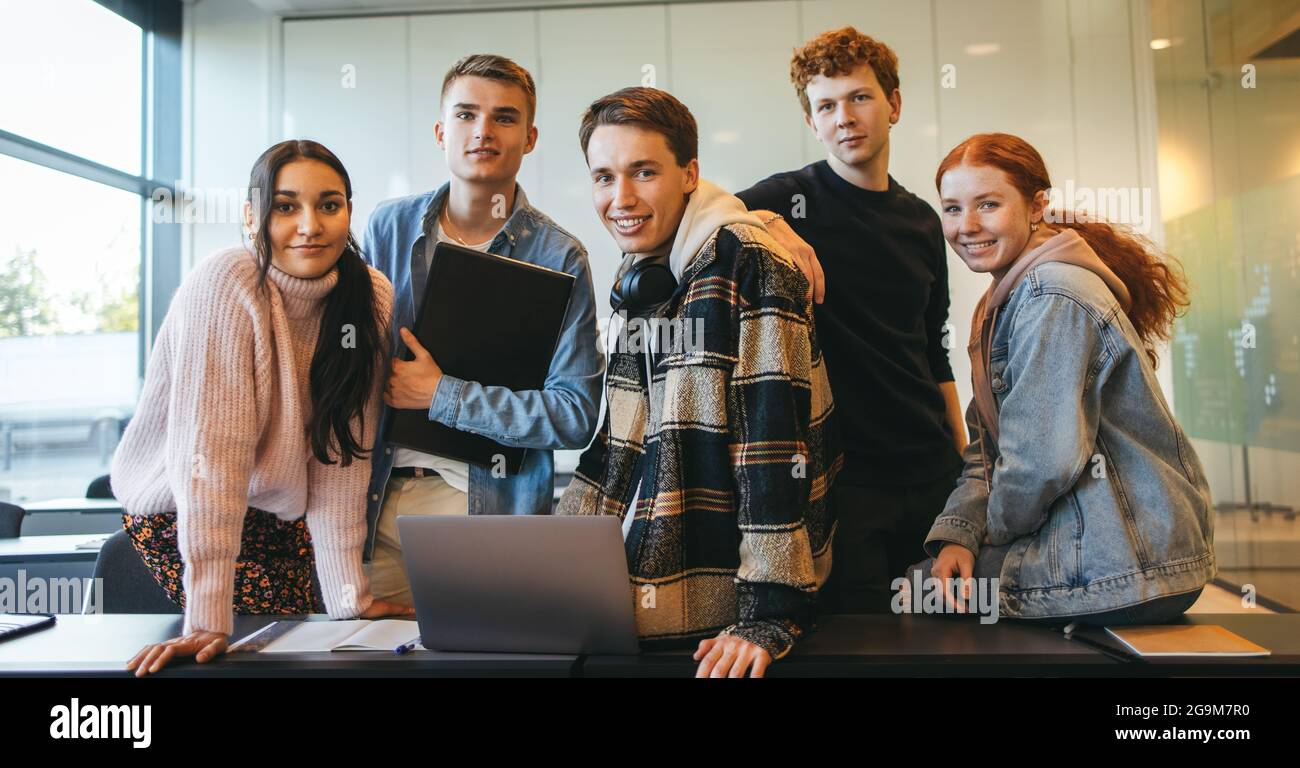 Students sitting during break in classroom and smiling at camera. Group ...