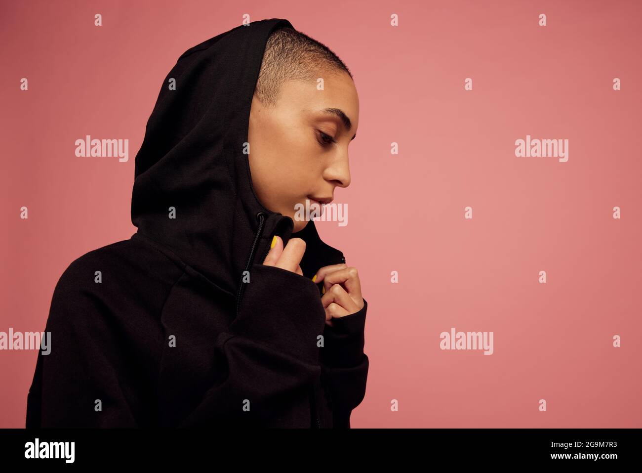 Gen Z female with shaved head on pink background. Androgynous woman in ...