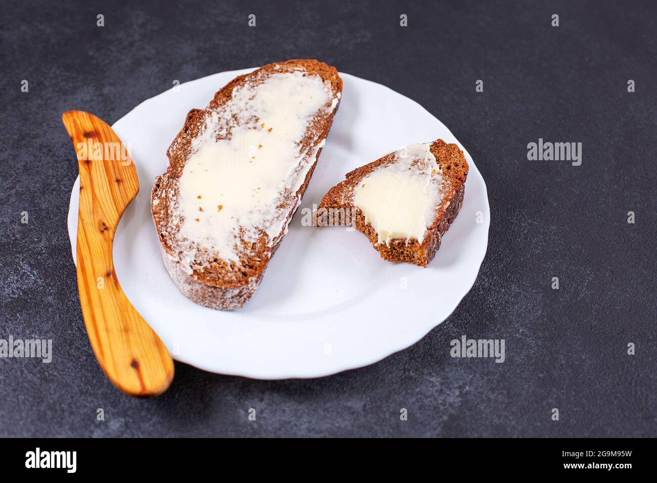 One whole slice of bread and butter and one A piece of bread with a ...