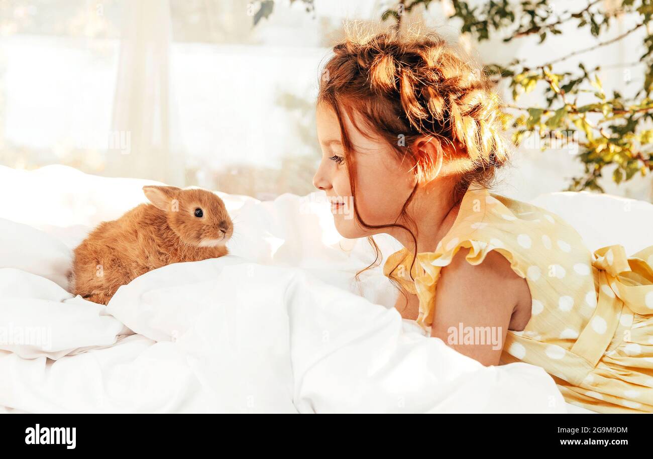 Little pretty girl in summer dress sitting outside on the bed with ...