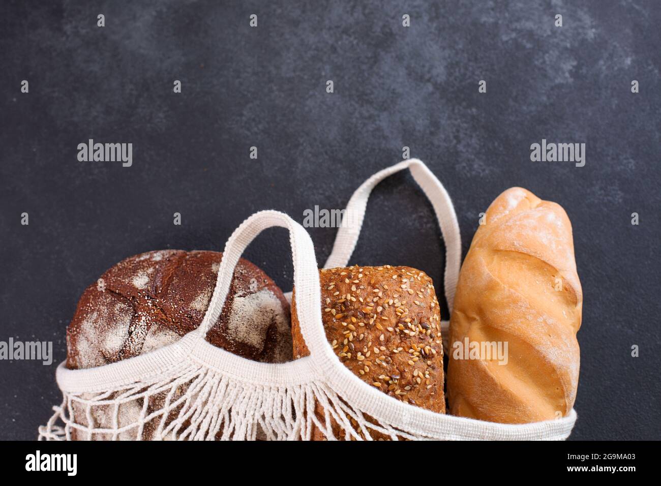Different kinds of fresh bread in white mesh tote bag on black ...