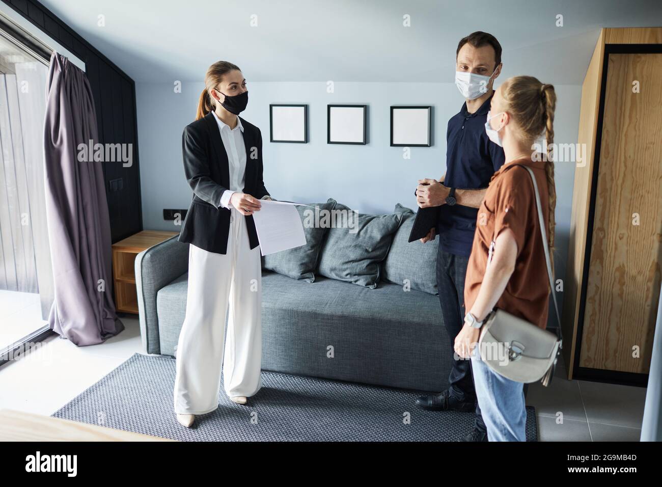 Full length side view portrait of female real estate agent wearing mask ...