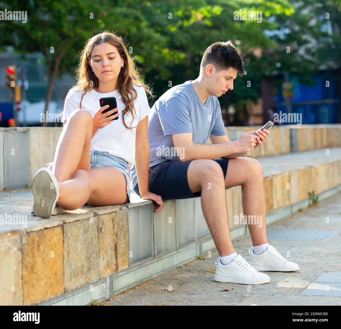 Two teenagers chatting on their smartphone on walking Stock Photo - Alamy