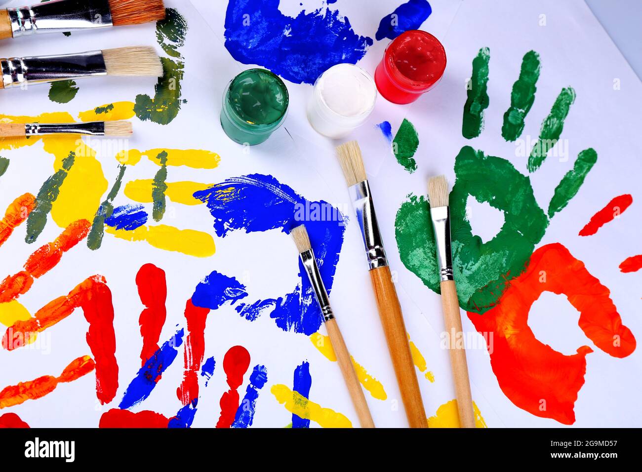 Hand prints of paint, paints and brushes on white background Stock ...