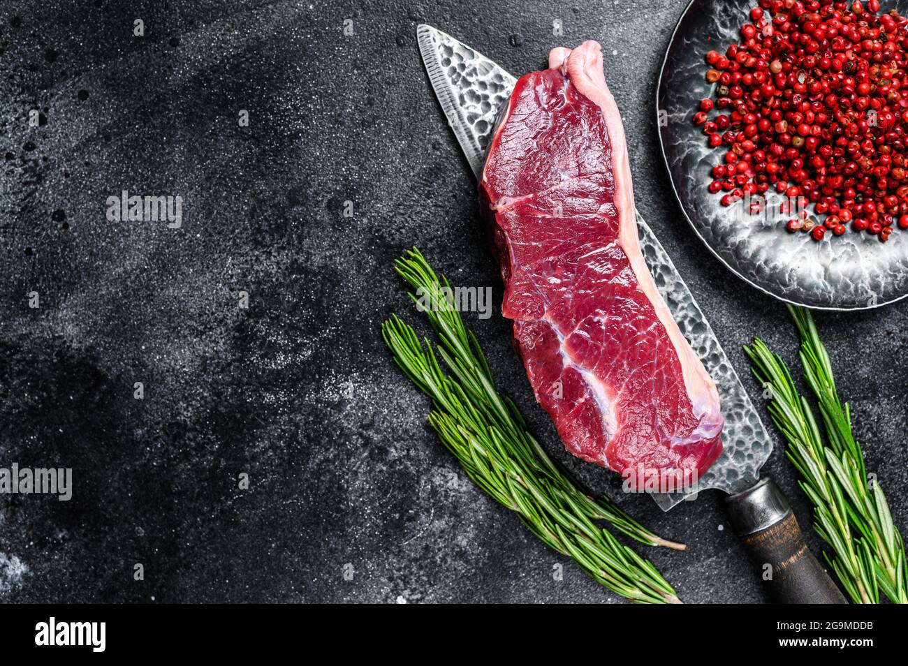 Raw marbled beef meat strip loin steak on a knife. Black background ...