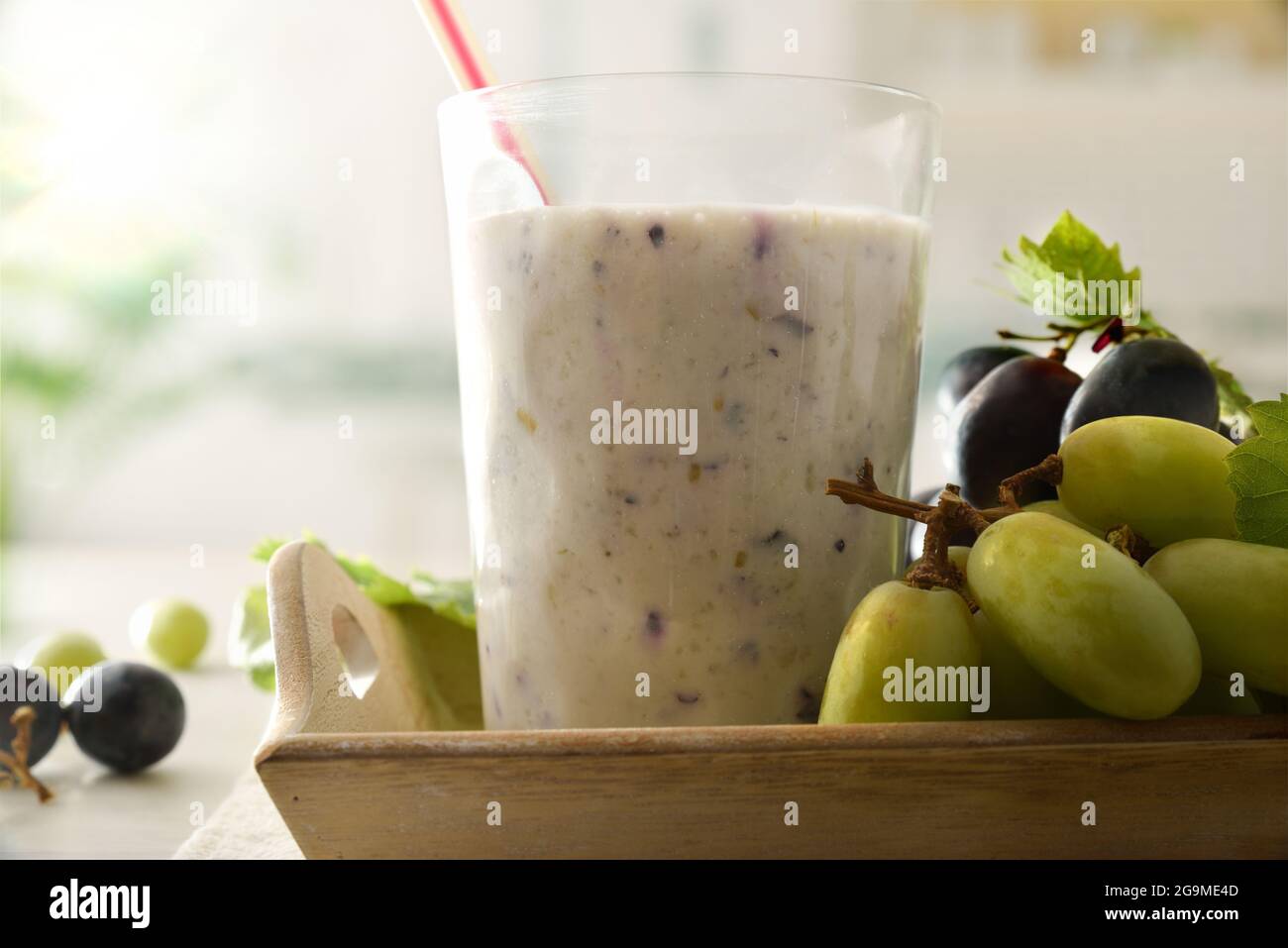 Organic liquid grape yogurt on white plate with bunches of white and ...