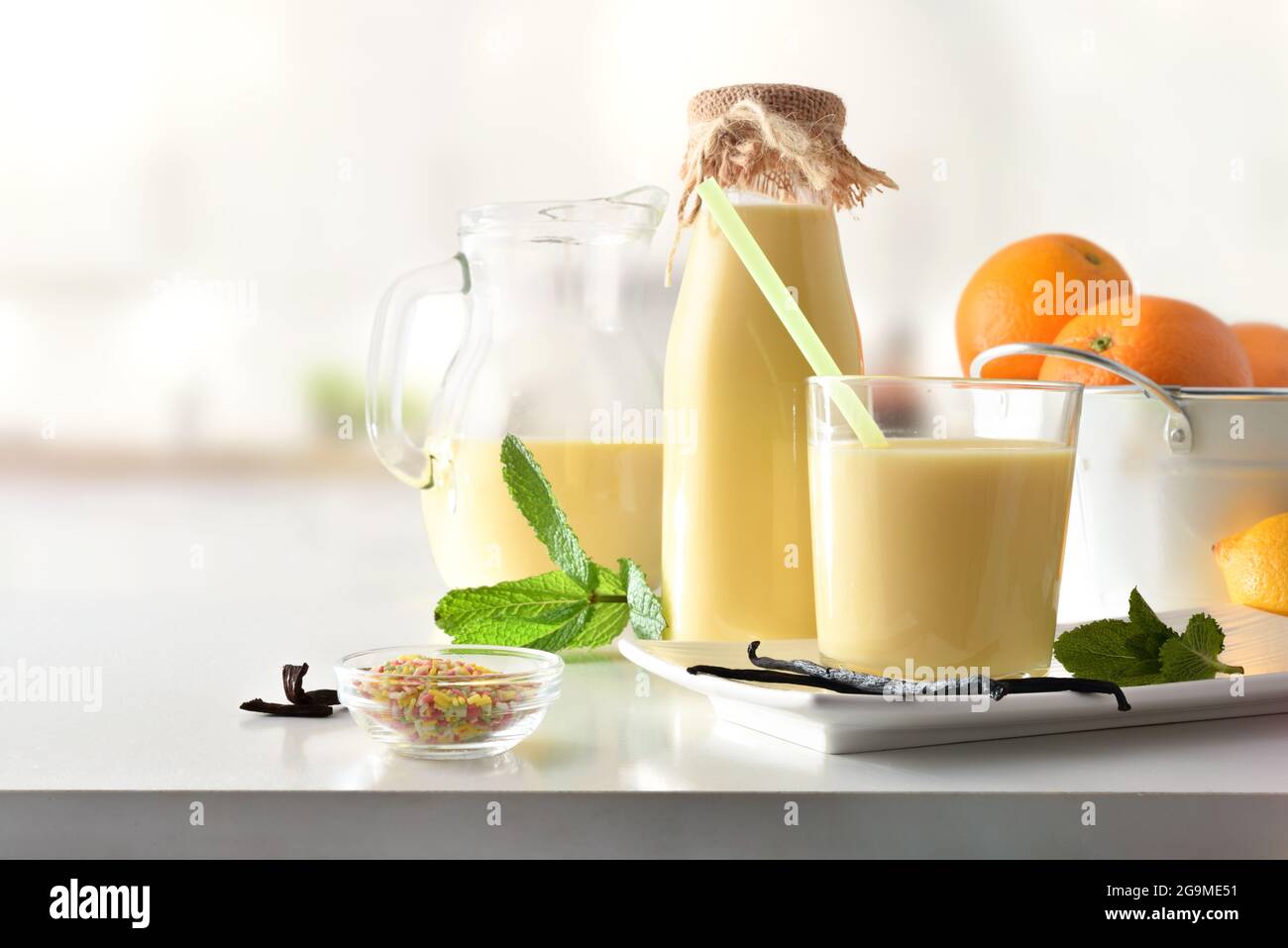 Milk drink with vanilla in glass containers on kitchen bench and ...