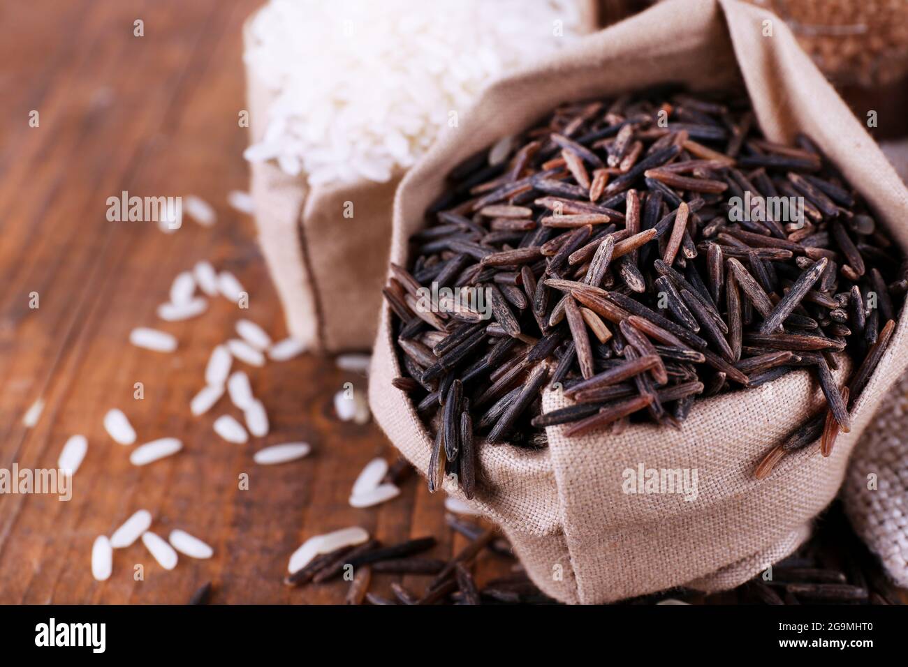 Different types of rice in sacks on wooden background Stock Photo - Alamy