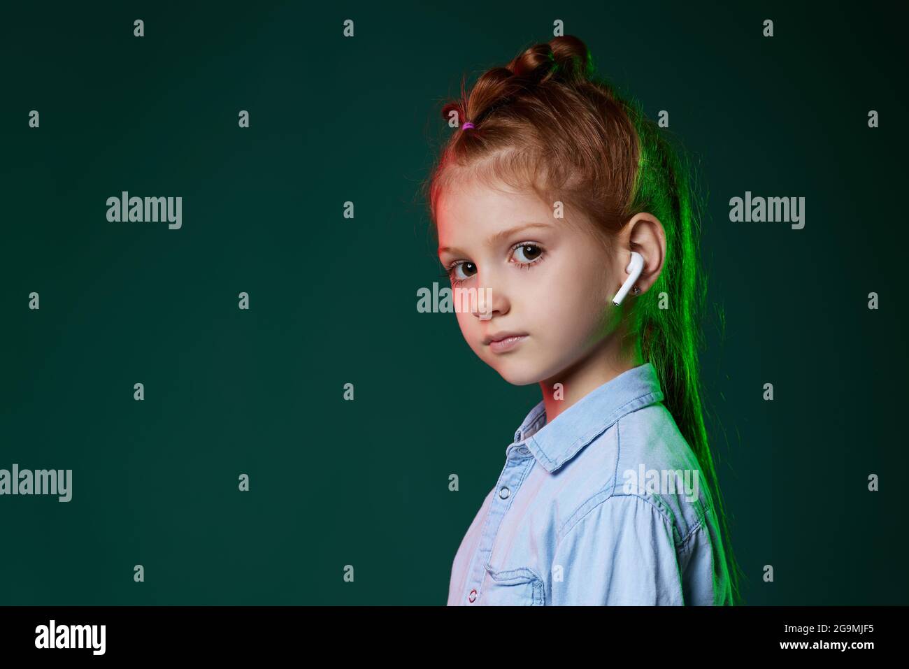happy redhead child girl in earphones listening to music on beige ...