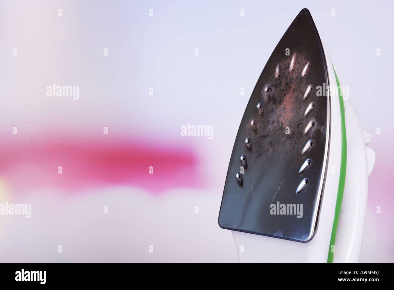 Flat iron with burnt mark on bright background Stock Photo - Alamy