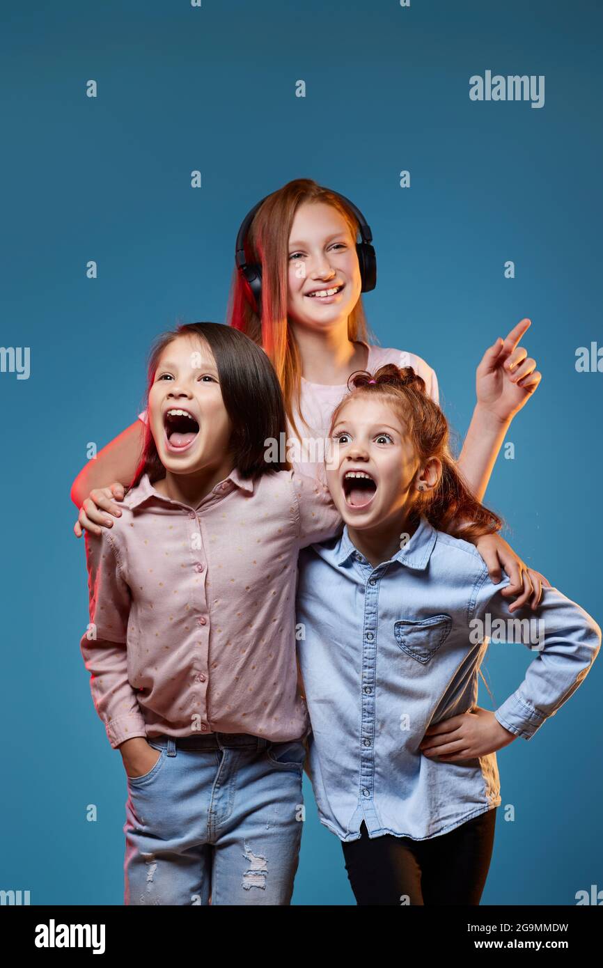 three kids girls standing together on blue background Stock Photo - Alamy