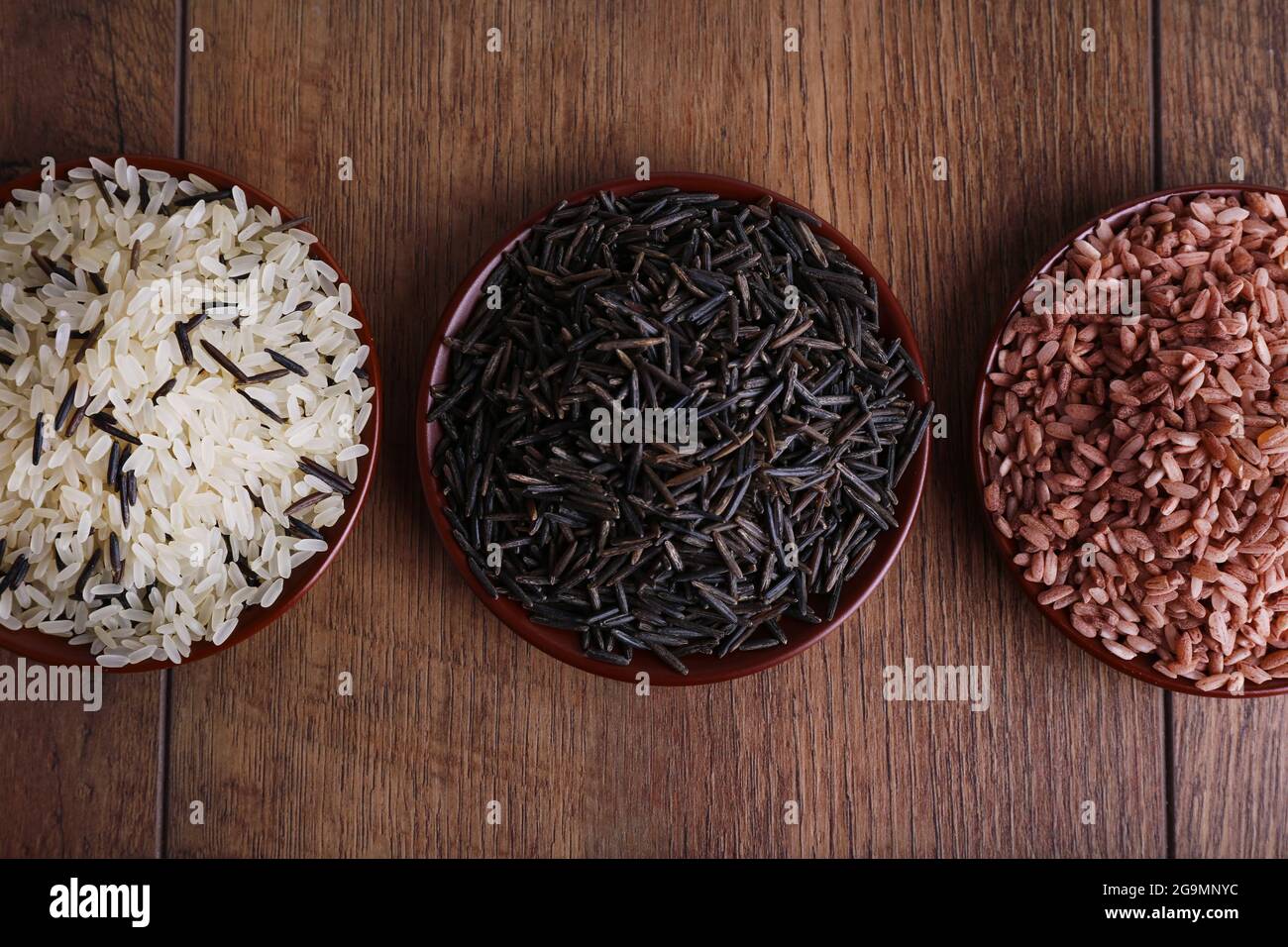 Different kinds of rice on plates on wooden background Stock Photo - Alamy