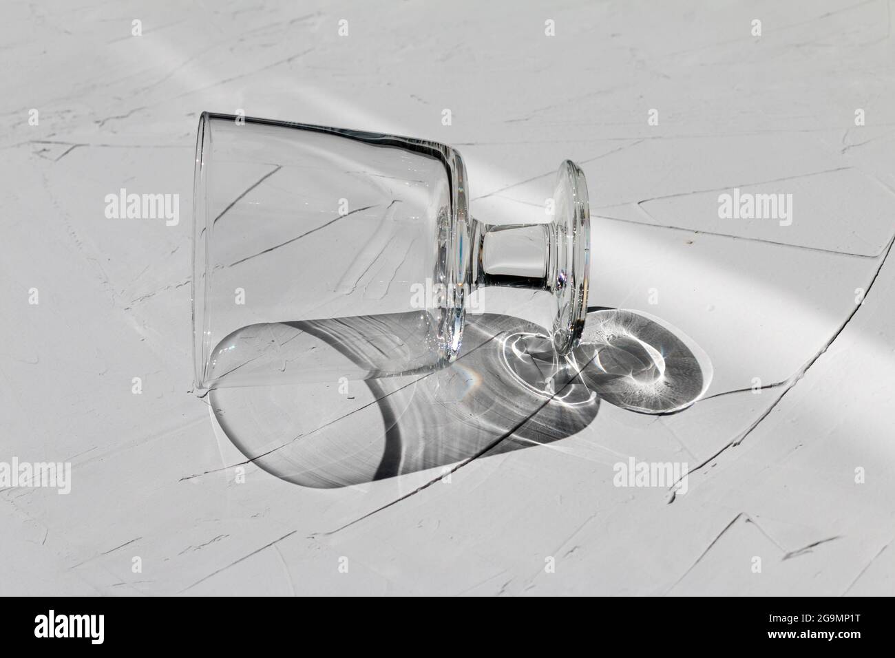 Glass on a grey concrete table with sunbeams and reflections, view from ...