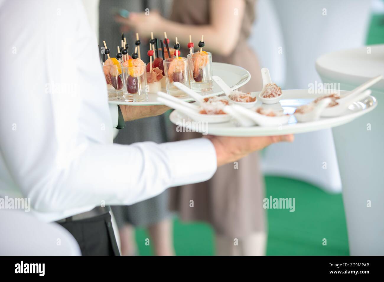 Waiter carrying plates with appetizers on some festive event, party or ...