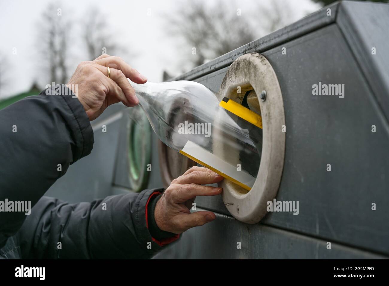Hands of a man throwing a bottle into the public glass container or ...