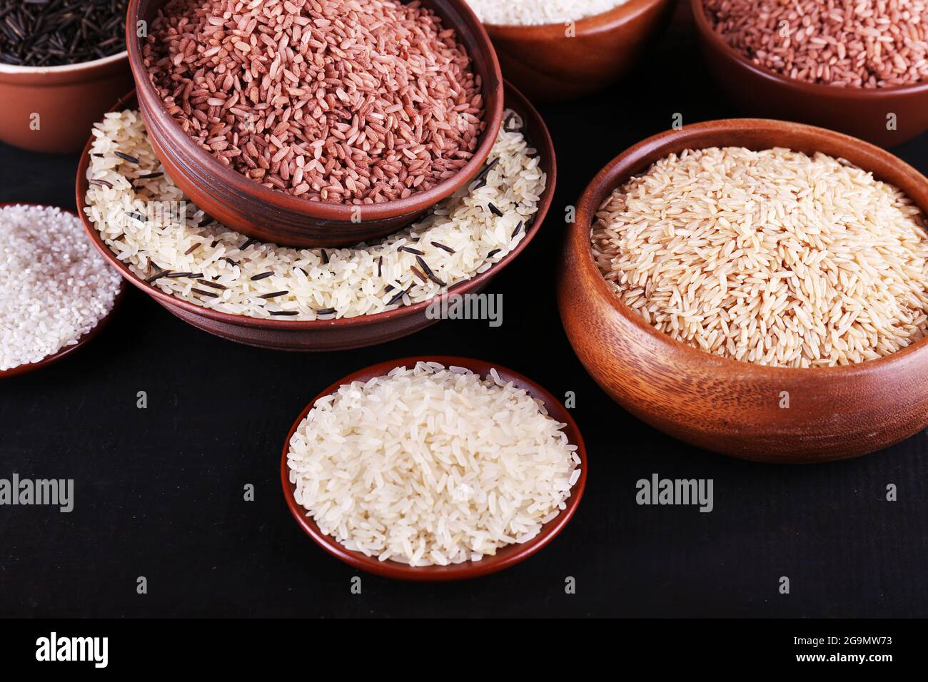 Different kinds of rice in bowls on wooden background Stock Photo - Alamy