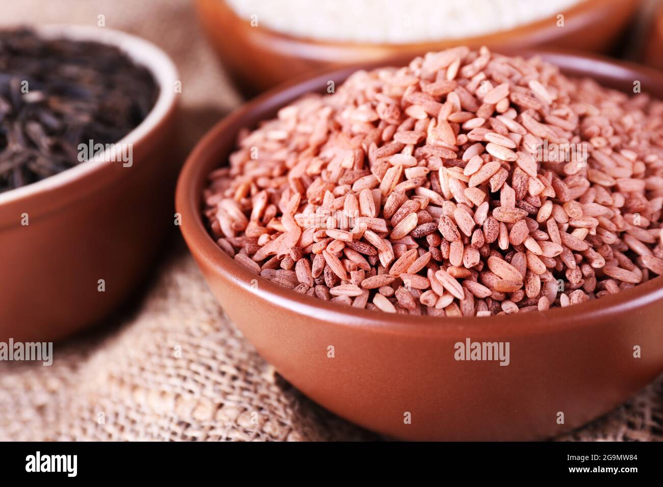 Different kinds of rice in bowls on sackcloth background Stock Photo ...
