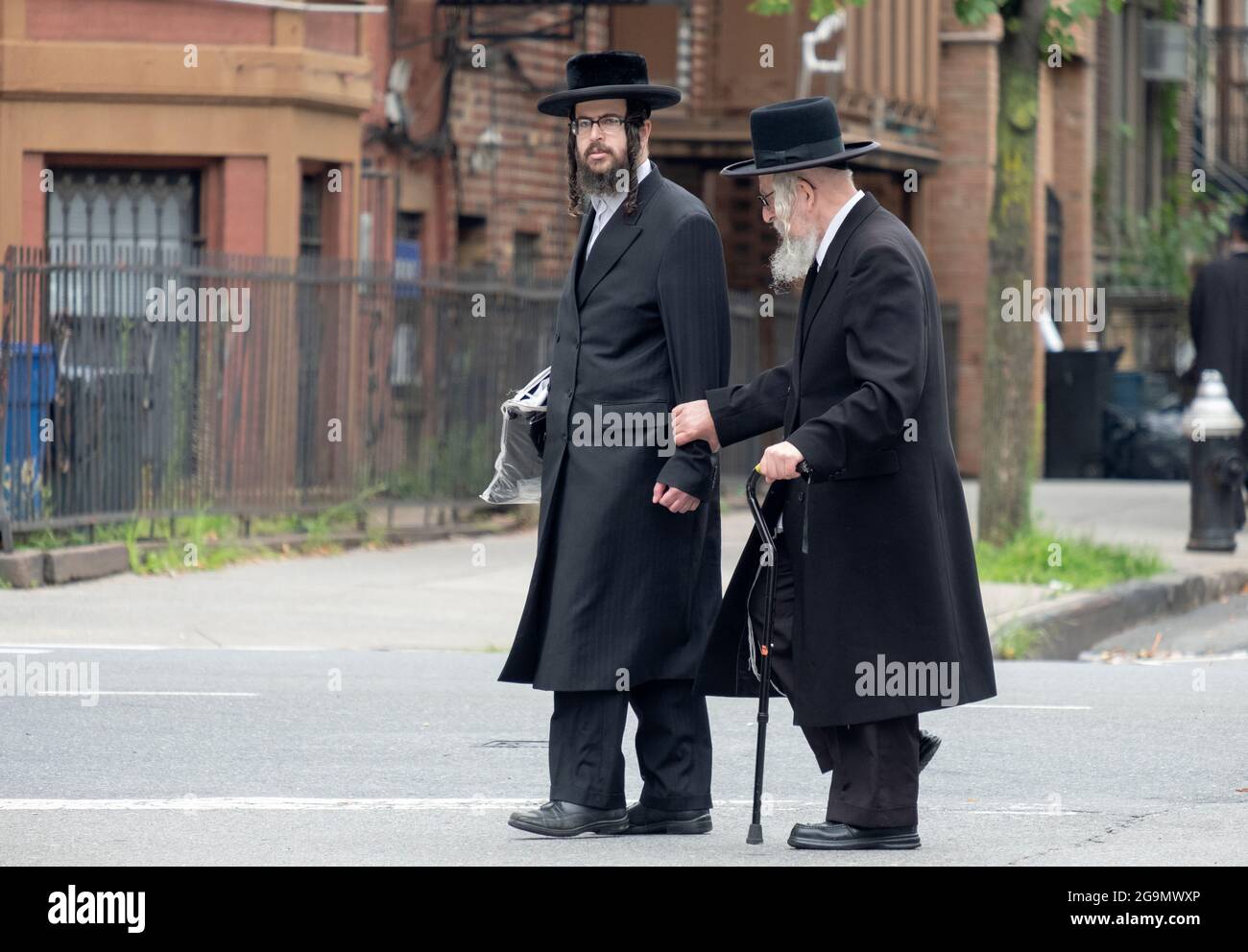 A young orthodox Jewish man helps an older one crossing the street. On ...