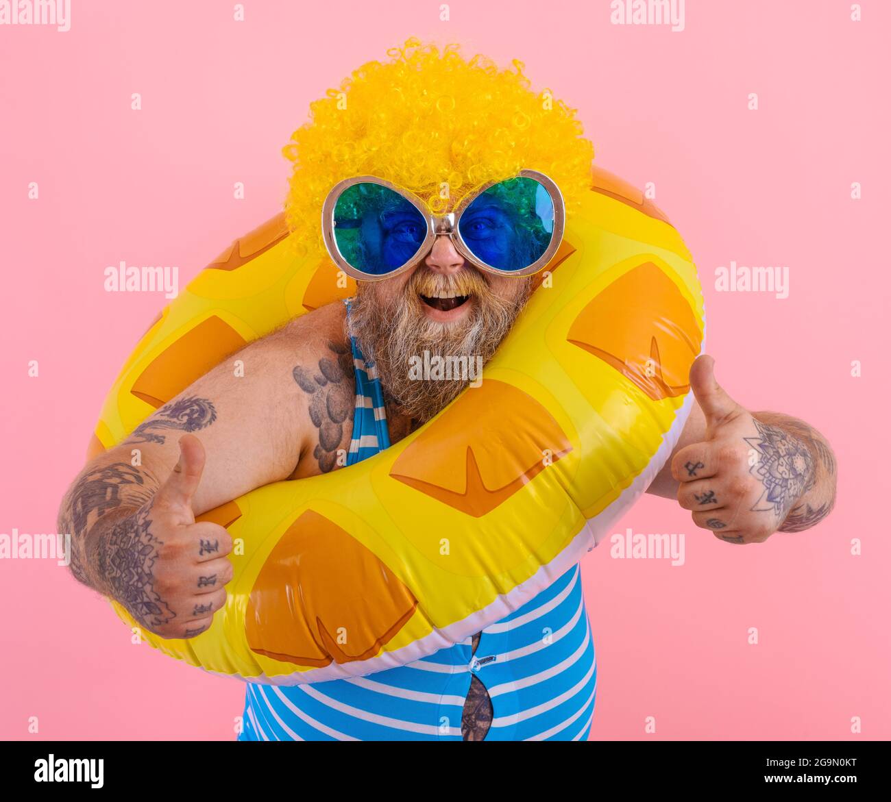Fat happy man with wig in head is ready to swim with a donut lifesaver ...