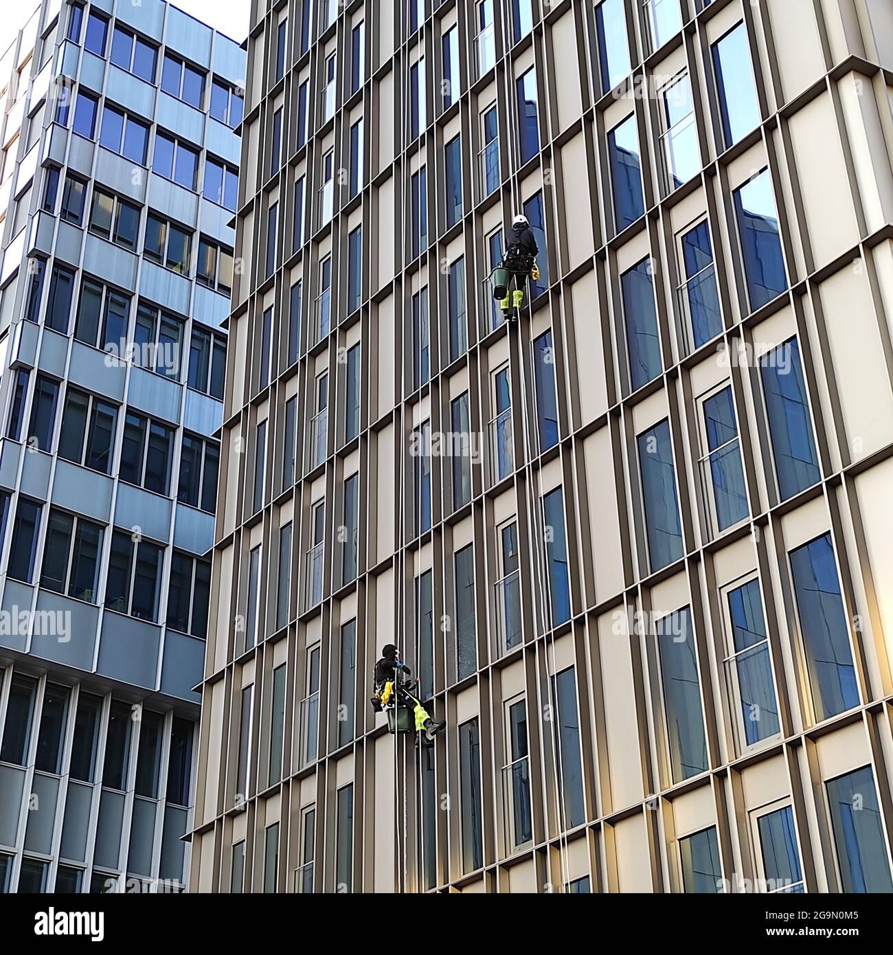 Closeup shot of a a skyscraper and two workers washing it's windows ...