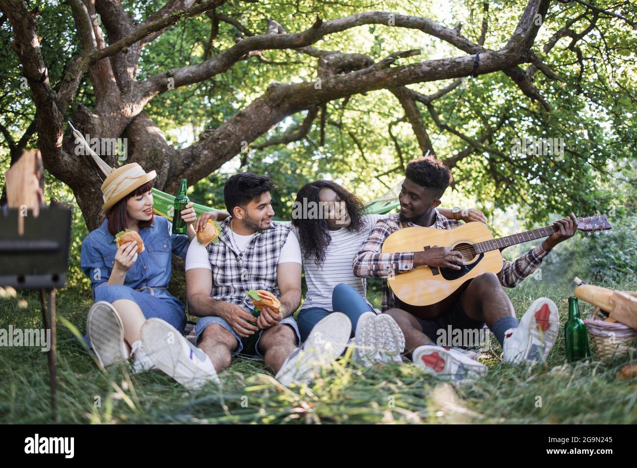 Carefree diverse people sitting at summer garden with fast food and ...