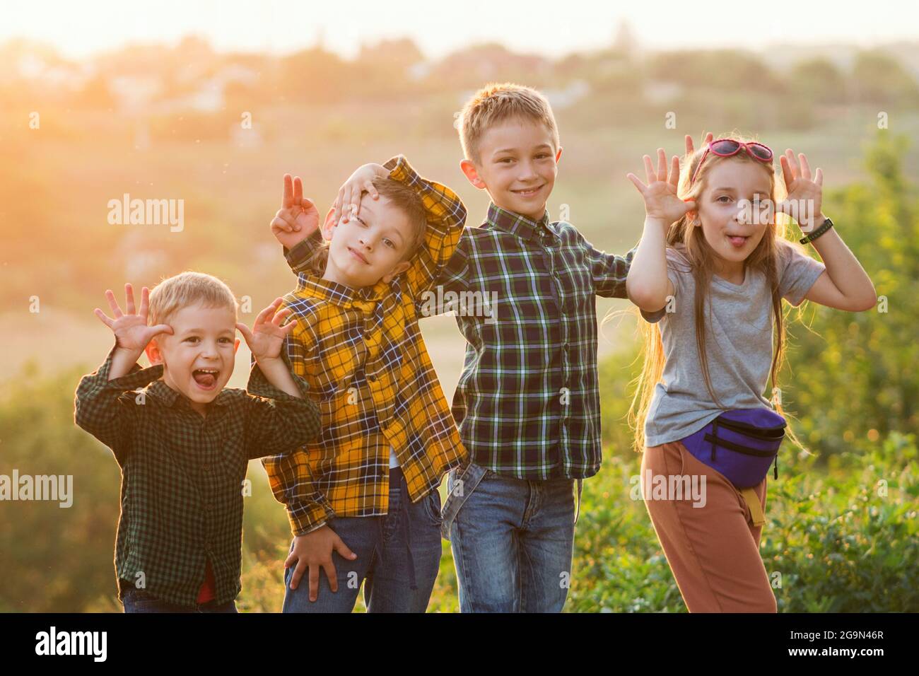 Three brothers and sister at sunset. Children grimace and smile while ...