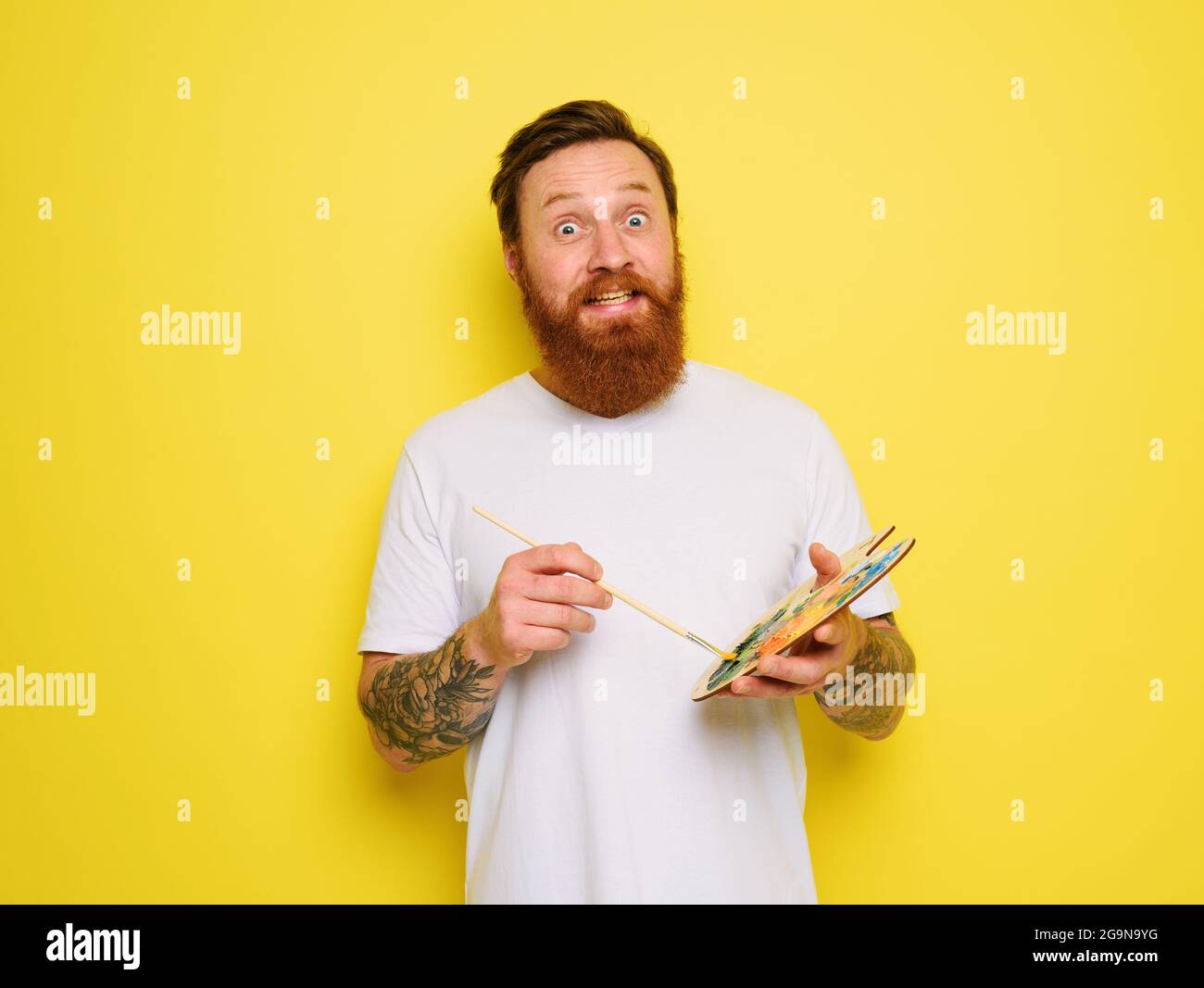 Doubter man with beard and tattoo is ready to draw with brushes Stock ...