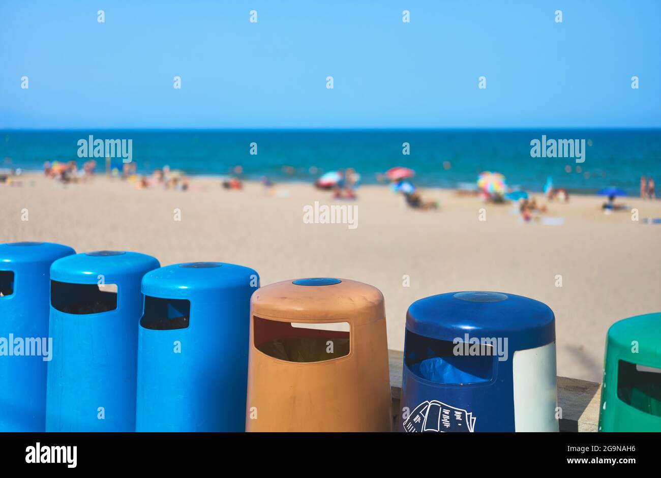 detail of waste containers in front of a beach with tourists with sea ...